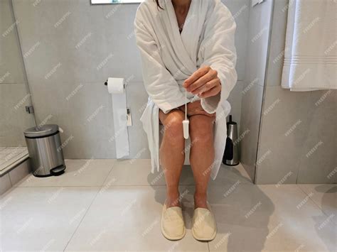 Premium Photo Woman Sits On The Toilet In Home Bathroom And Takes Out