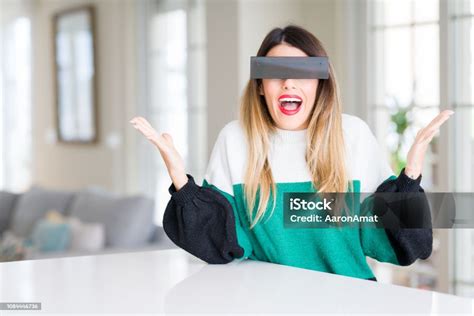 집에서 검은 검열 밴드와 아름 다운 젊은 여 자가 눈가리 개 눈 그리고 팔 제기 미친 및 성공을 위한 놀을 축 하 눈 흥분 비명 우승자 개념 가리기에 대한 스톡 사진 및