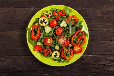 Tamata 오이 양상추 양파와 Arugula 나무 테이블에의 신선한 야채와 야채 샐러드 유리 그릇에 녹색 신선한 야채와 함께