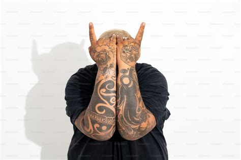 A Man With Tattoos Covering His Face With His Hands Photo Portrait