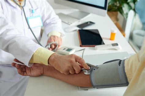 Médico que mide la presión arterial del paciente con tonómetro durante el chequeo anual Foto