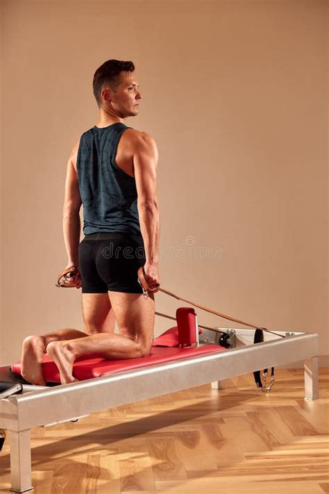 Side View Of Barefoot Male Athlete Lying On Pilates Reformer And