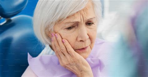 화가 난 노부인은 손바닥을 오른쪽 뺨에 대고 메모를 하는 사람에게 치과 문제에 대해 이야기합니다 사진 Unsplash의