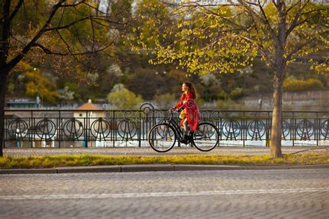 Woman In Red Rain Coat Outdoors On City Street Riding Bicycle Stock