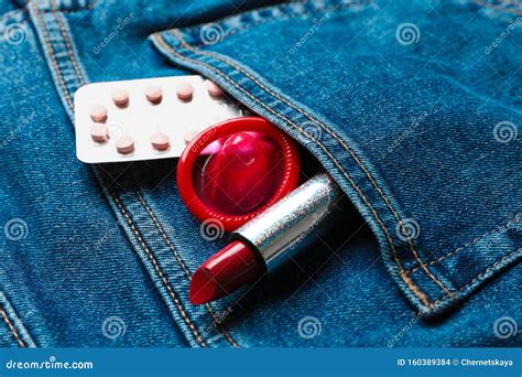 Red Lipstick With Condom And Birth Control Pills In Pocket Of Jeans Safe Sex Concept Stock