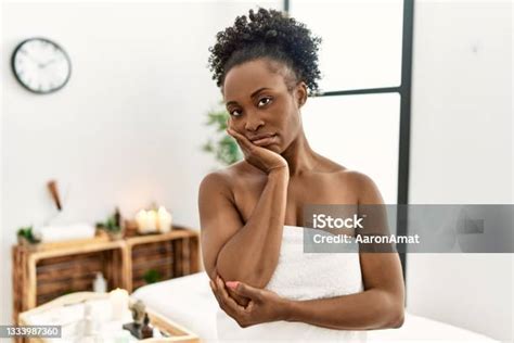 미용 센터에 서 수건을 입고 젊은 아프리카 계 미국인 여자 는 지치고 교차 팔에 우울증 문제로 지루해 보이는 생각 건강한 생활
