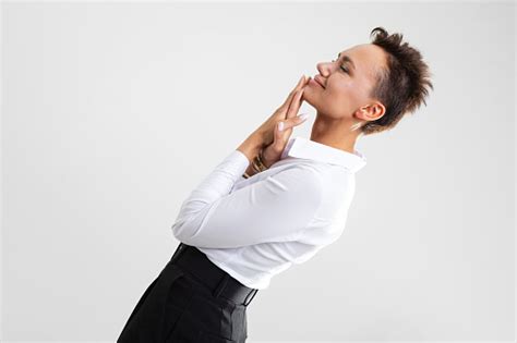 짧은 어두운 머리를 가진 젊은 아름다운 소녀 흰색 셔츠 검은 바지에 메이크업 시계와 손을 넣어 팔찌와 흰색 매니큐어와 미소