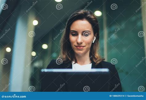 Successful Female Banker Using Tablet And Wireless Earphones Outdoors