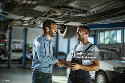 Cliente Feliz Que Agita As Mãos Com Auto Mecânico Em Uma Oficina Foto