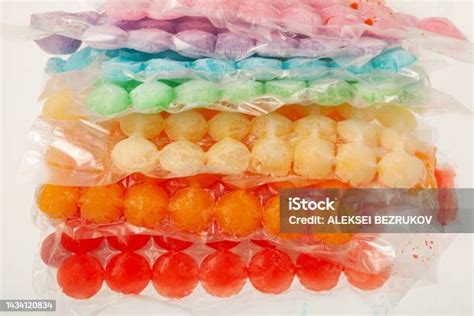 냉동 클로즈업을 위한 플라스틱 일회용 가방에 담긴 여러 가지 빛깔의 얼음 조각 냉동 과일 주스 칵테일 또는 여름 상쾌한 음료를위한 무지개 얼음 각얼음에 대한 스톡 사진 및