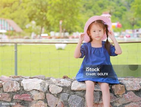 귀여운 아시아 소녀는 녹색 공원에 대 한 돌 벽에 밀 짚 모자를 착용 귀여운에 대한 스톡 사진 및 기타 이미지 귀여운 녹색