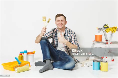 재미 흰색 배경에 고립 된 페인트 브러시와 바닥 재건축 아파트 룸 악기에 앉아 남자 행복 한 미소 벽지 액세서리를 붙이기 그림 도구 수리 가정 개념입니다 개선에 대한 스톡