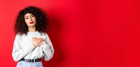 Hermosa mujer con cabello rizado sintiéndose tocada y agradecida cogidos de la mano en el