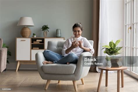 아름다운 인도 여성은 안락 의자에서 편안한 스마트 폰을 사용합니다 가정 생활에 대한 스톡 사진 및 기타 이미지 가정 생활