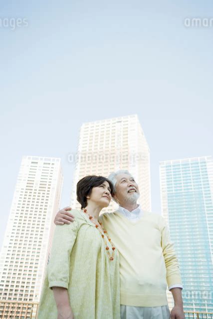 ビルを背に肩を寄せ合い空を見上げるシニア夫婦の写真素材 Fyi03360928 ストックフォトの Qlean Market
