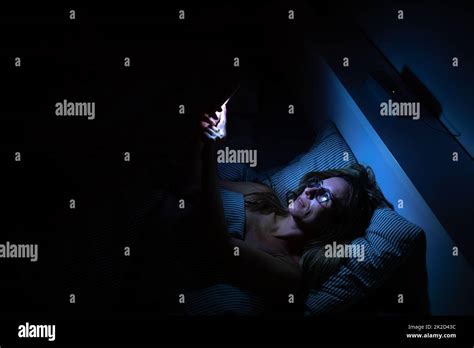 Pretty Middle Aged Woman Using Her Cell Phone In Bed At Night