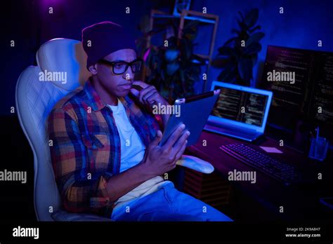 Photo Of Intelligent Hacker Sitting Chair Use Tablet Operating Database Evening Loft Office