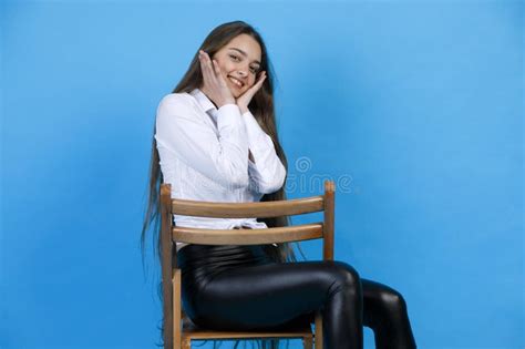 Happy Female Model In Shirt Holding Hands On Face While Sitting On