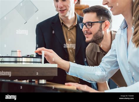 Couple Testing A Hi Fi System In The Store With The Salesman Explaining Stock Photo Alamy