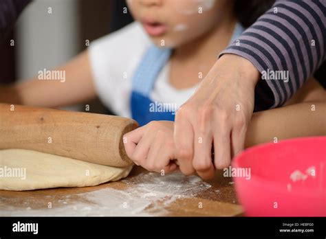 Mother Teaching Her Daughter Making Bread With Rolling Pin On The