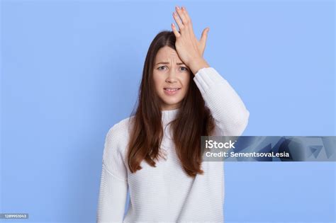 걱정스러운 표정으로 카메라를 바라보며 손바닥을 들고 있는 잊혀진 젊은 여성이 파란 배경에서 고립된 포즈를 취하는 중요한 것을