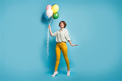 재미 있는 예쁜 아가씨 산책 깜짝 생일 파티 의 전체 길이 사진 많은 공기 풍선 캐주얼 녹색 셔츠 노란색 바지 신발 고립 된