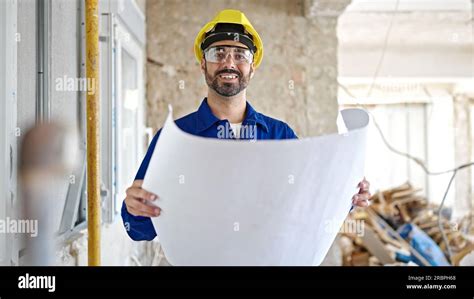Young Hispanic Man Worker Wearing Hardhat Reading House Project At