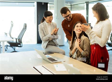 In A Contemporary Workspace Colleagues Share Smiles And Applause