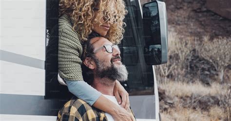 목적지에서 사랑에 빠진 행복한 커플과 함께 차량 컨셉의 라이프스타일로 여행하세요 여자는 수염을 가진 남자를 껴안는다 배경의 자연 제단 원주민 휴가를위한 밴 캠핑카 차량