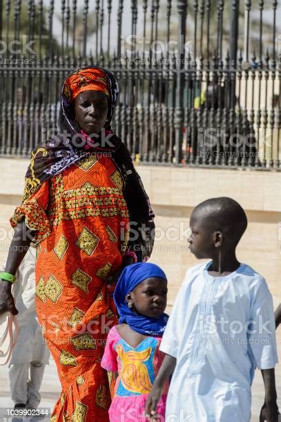 Touba Mouride 형제 애의 집의 큰 모스크에에서 미확인된 세네갈 여자 색 전통 옷을 입고 산책 건축에 대한 스톡 사진