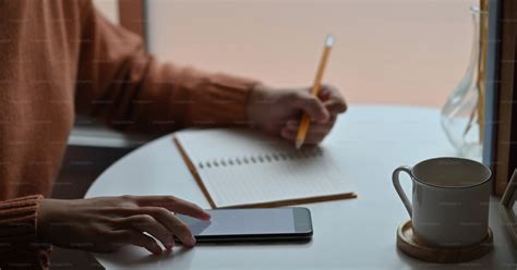 편안한 거실 위의 흰색 작업 책상에 앉아 메모를 하는 매력적인 여성의 자른 이미지 사진 Unsplash의 태국 이미지