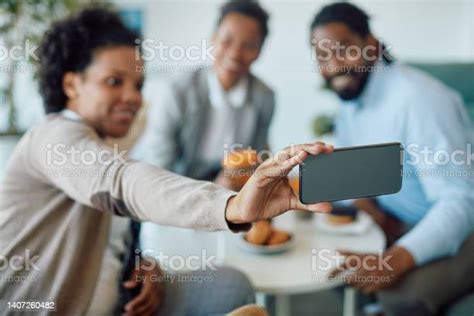 스마트 폰으로 셀카를 찍는 흑인 비즈니스 동료의 클로즈업 Brand Name Smart Phone에 대한 스톡 사진 및 기타 이미지 Brand Name Smart