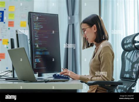 Asian Prompt Engineer Develop Coding App With Software Data Sitting In Front Of Computer Monitor