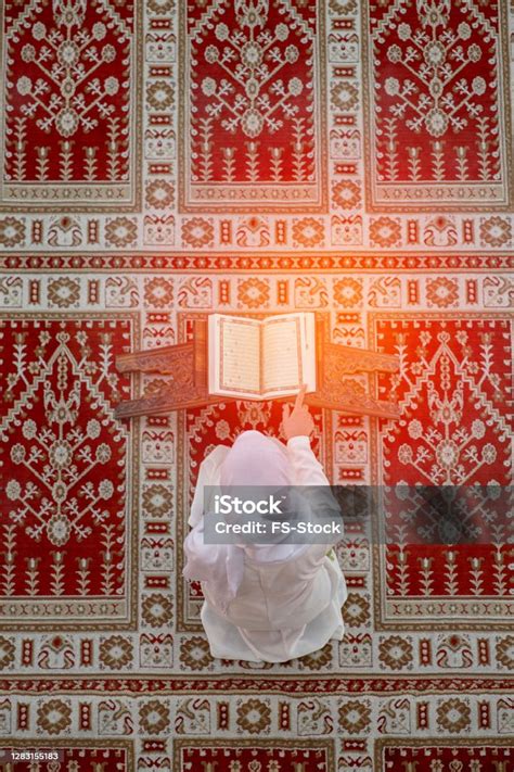 모스크에서 꾸란을 읽고 창문에서 떨어지는 햇빛을 읽는 젊은 무슬림 여성 Eid Ul Fitr에 대한 스톡 사진 및 기타 이미지