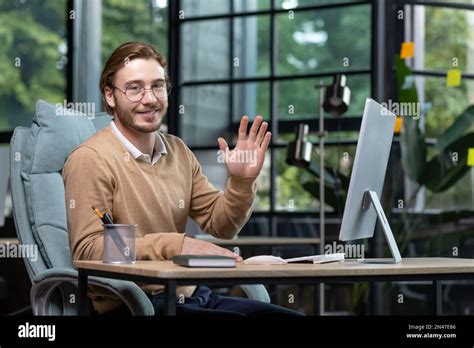 Portrait Of A Young Businessman Designer Programmer In A Busy Office Sitting At A Table With A
