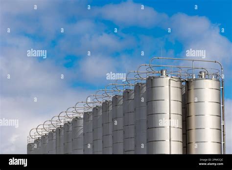 Stainless Steel Silos Against The Blue Sky Warehouses For Storage Of Plastics And Bulk Grains