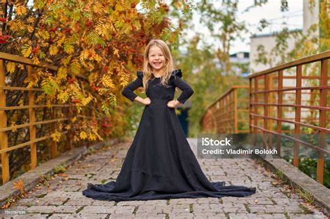 긴 검은 색 패션 드레스에 가을 흔적에 행복한 웃음 어린 소녀 화려한 공주 드레스에 할로윈 복고풍 정장과 미소 할로윈에 마녀 의상을 입고 웃는 재미있는 아이 소녀 마녀에