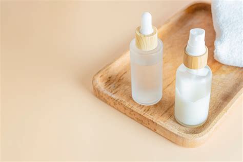 스킨 케어 화장품 세트 크림 펌프 병 및 에센스 병 나무 접시에 미용 혈청 또는 유체와 복사 공간이 있는 베이지색 배경에 스파