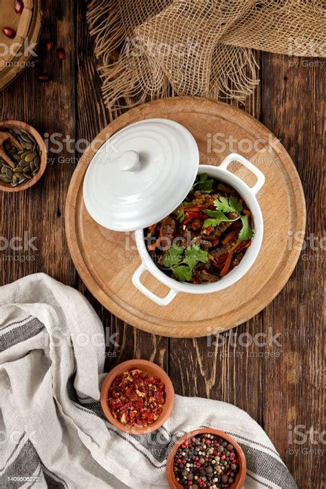 나무로 된 소박한 배경에 세라믹 냄비에 야채와 함께 쇠고기 Ragout 그루지야 스타일의 캐서롤에 고수풀 잎이 달린 스튜 고기