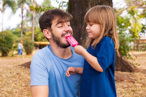 Pai e filha no parque chupando um delicioso picolé Foto Premium