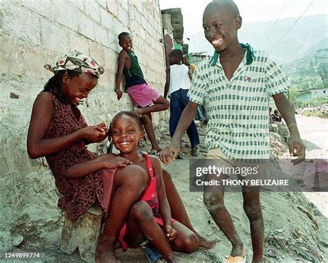 A Young Girl Braids The Hair Of Her Young Sister While Other