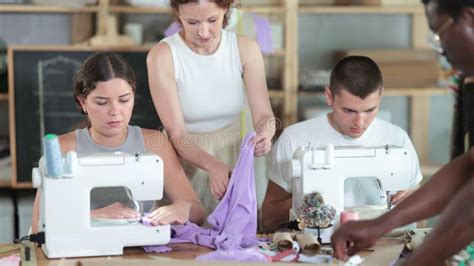 Kind Middle Aged Female Teacher Helping Students Sew While Other Works