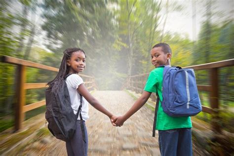 Premium Photo Cute Pupils Holding Hands Against Bridge With Railings