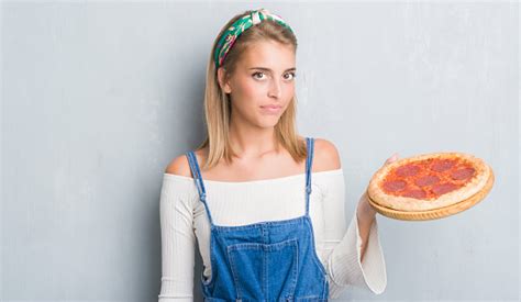 스마트 얼굴 심각한 생각에 자신감이 식 페퍼로니 피자를 먹는 그런 지 회색 벽에 아름 다운 젊은 여자 감정에 대한 스톡 사진 및 기타 이미지 Istock