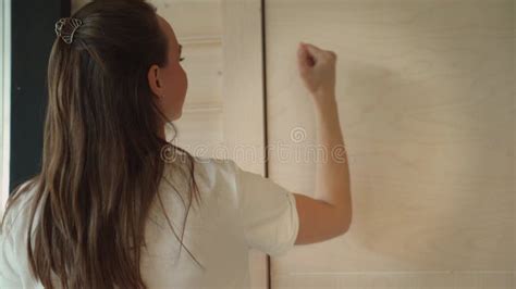 Woman Knocks On A Wooden Door Standing In The Doorway Rear View Of A