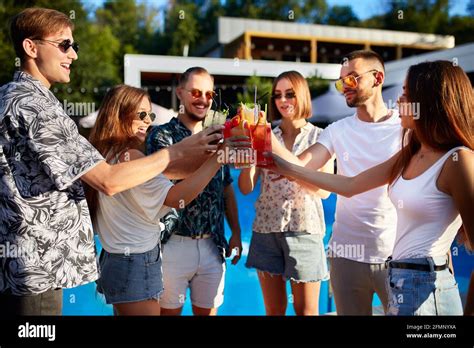 Group Of Friends Having Fun At Poolside Summer Party Clinking Glasses