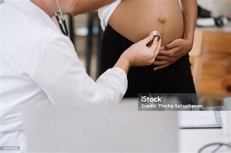 행복한 임산부는 병원에서 의사와 약속을 잡았습니다 청진기를 착용한 남성 의료진이 엄마 뱃속에서 아기의 심장 박동을 듣고 있다 임신 건강 관리 개념 20 24세에 대한 스톡