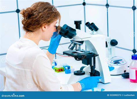 Young Woman Scientists Working With Microscope In Microbiology