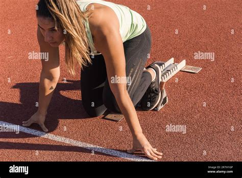 Young Female Athlete Beyond Start Line Assuming Crouching Start