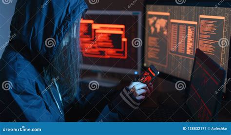 Girl Hacker In The Hood Holding The Phone In Hands Trying To Hack The